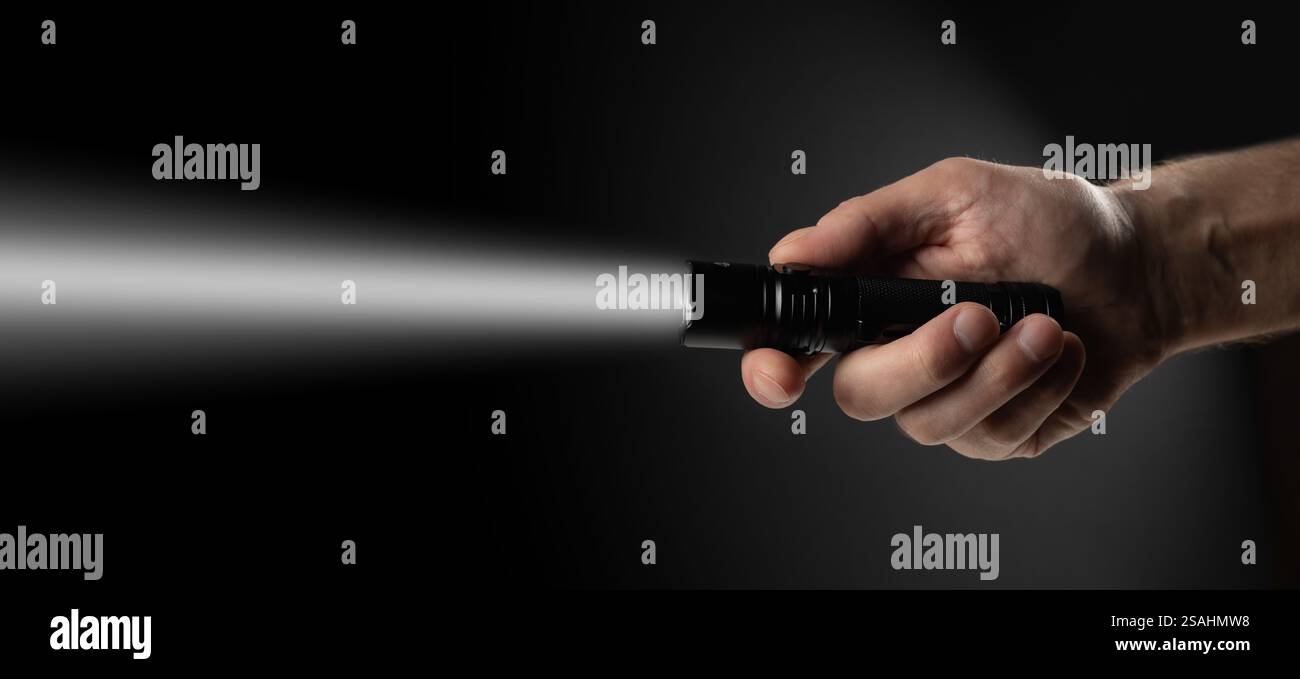 Black flashlight in human hands on a black background, including a ...