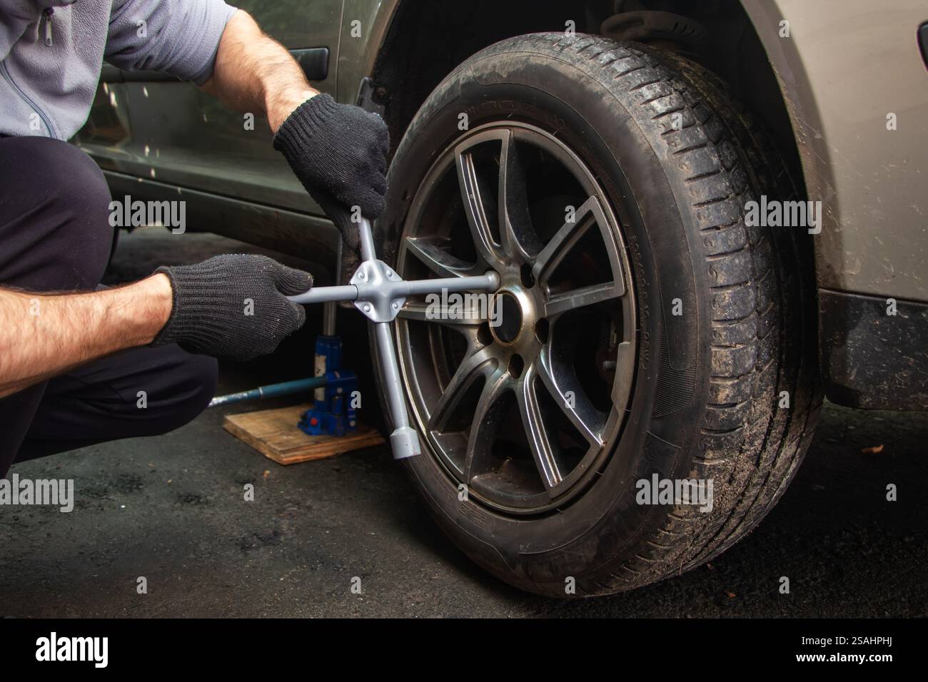 Car mechanic hand using cross wrench to uninstallation the wheel nuts ...