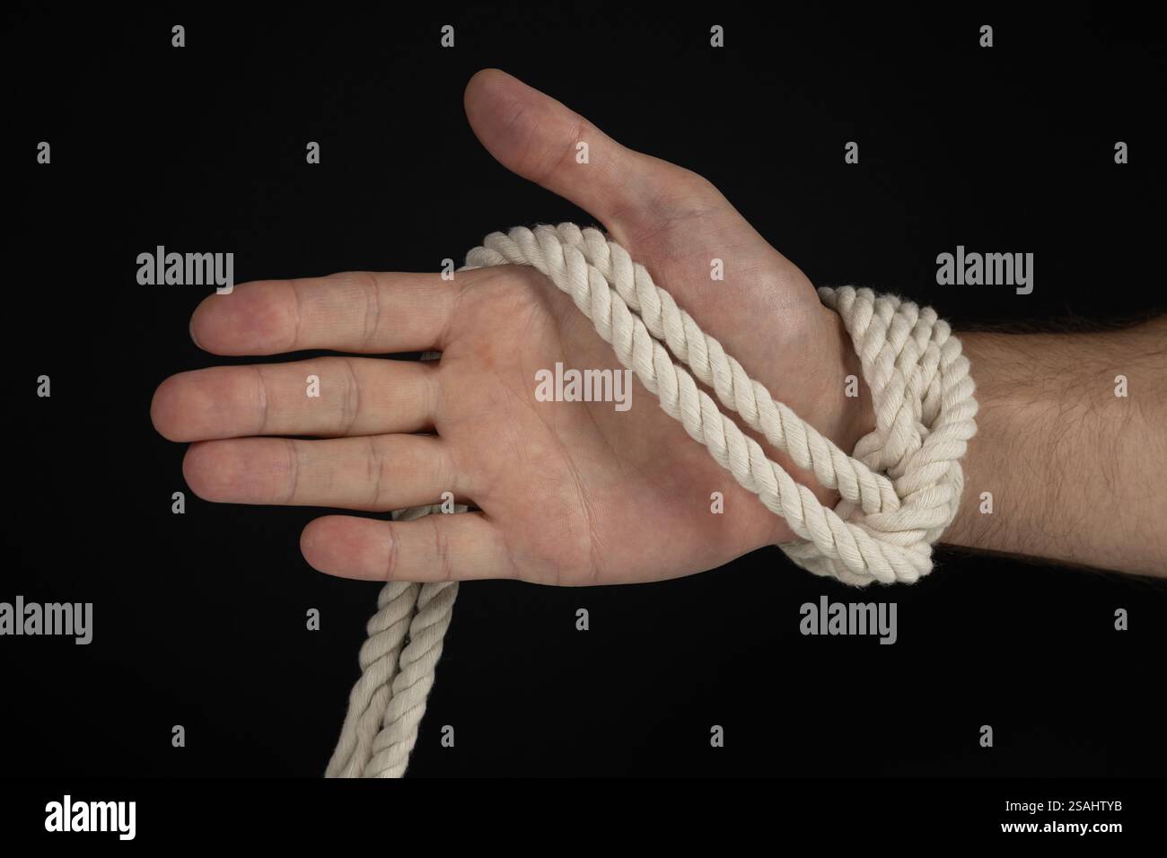Man's hand tied with a rope, vintage effect photo with noise. Pulling ...