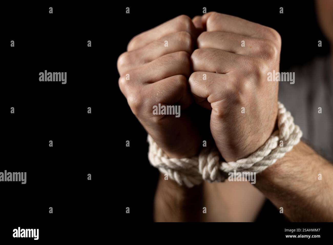Tied together hands of hostage on dark background Stock Photo - Alamy