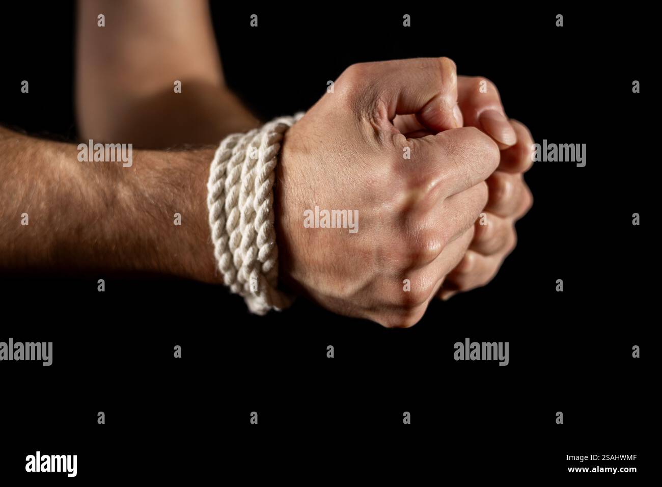 Tied together hands of hostage on dark background Stock Photo - Alamy