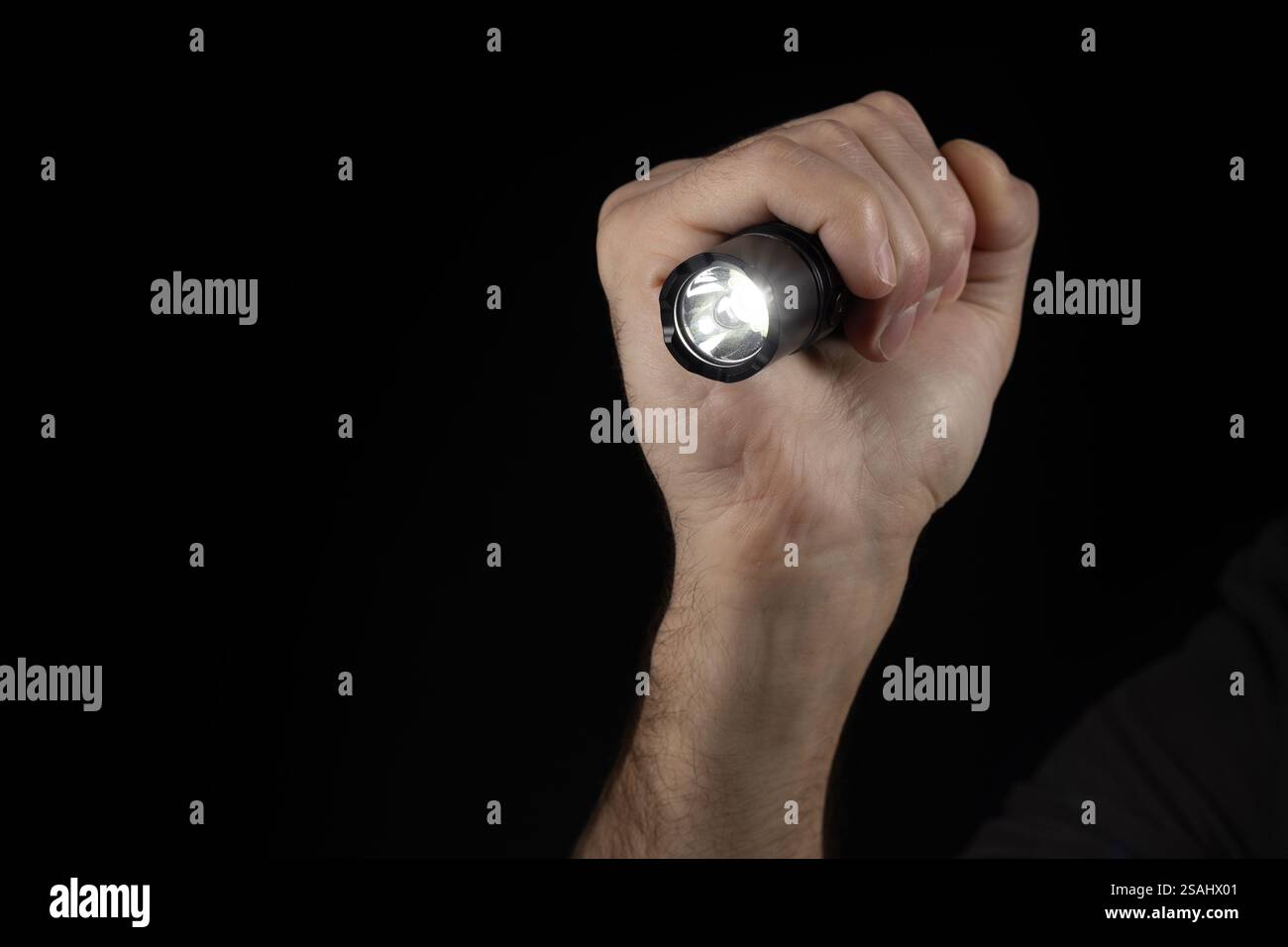 Black flashlight in human hands on a black background, including a ...