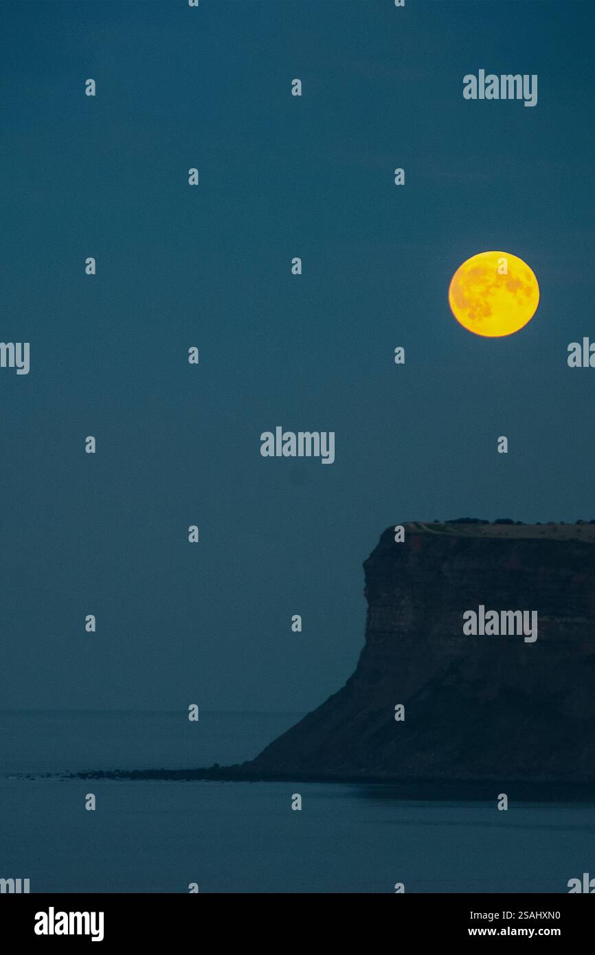 full moon rising over hunt cliff and the north sea Stock Photo - Alamy