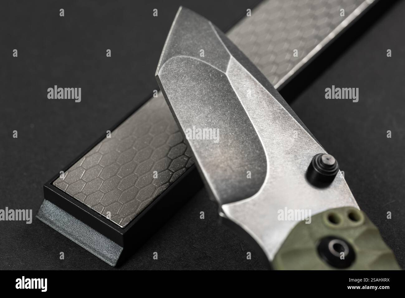 Man sharpens a knife using a whetstone on a dark table Stock Photo - Alamy