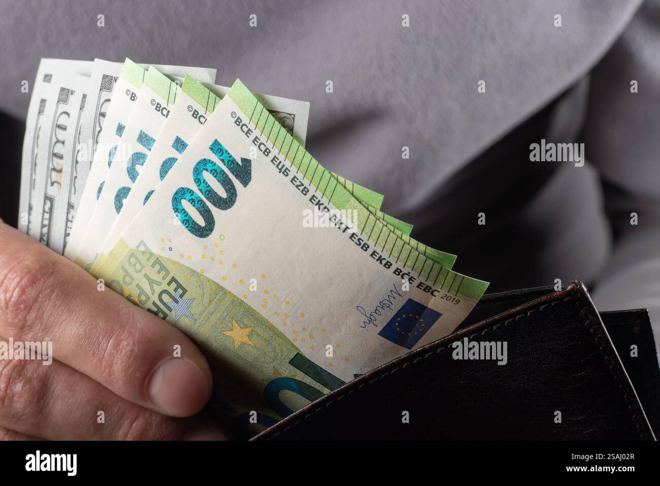 Man handing wallet with 100 euro and 100 dollars banknotes Stock Photo ...