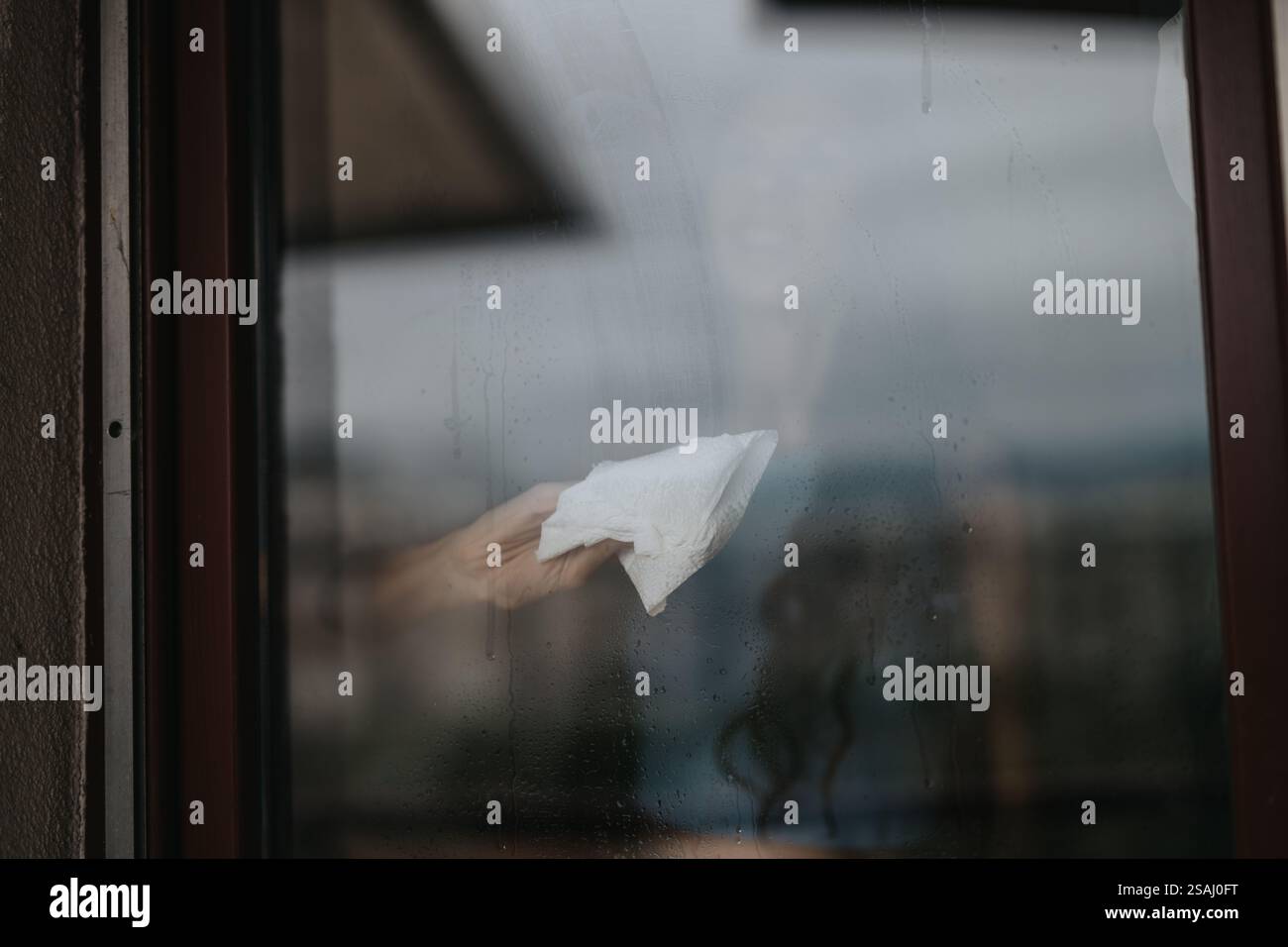 Hand cleaning a glass window with a paper towel on a rainy day Stock ...