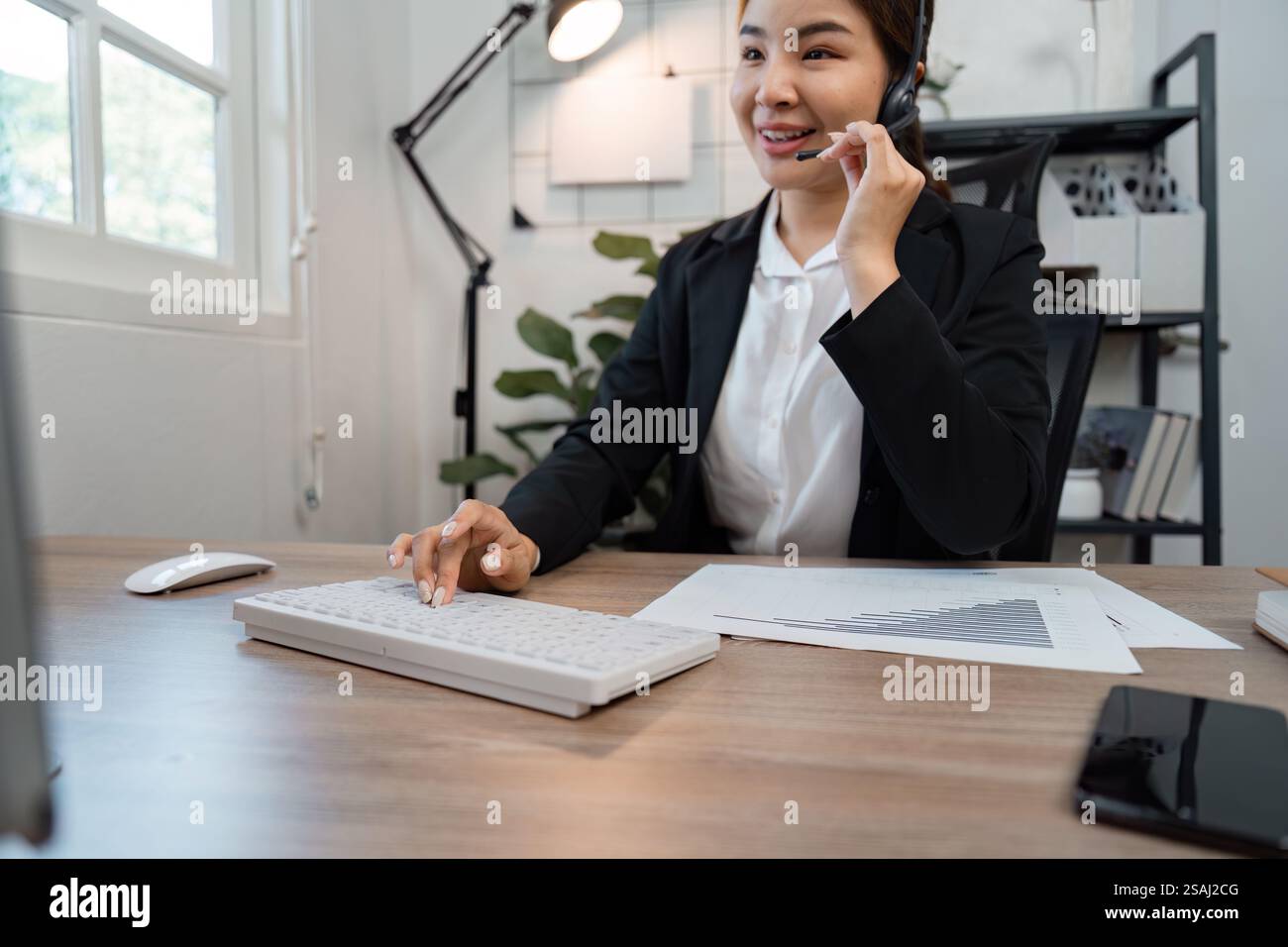 Professional Asian female call center agent assisting clients with ...