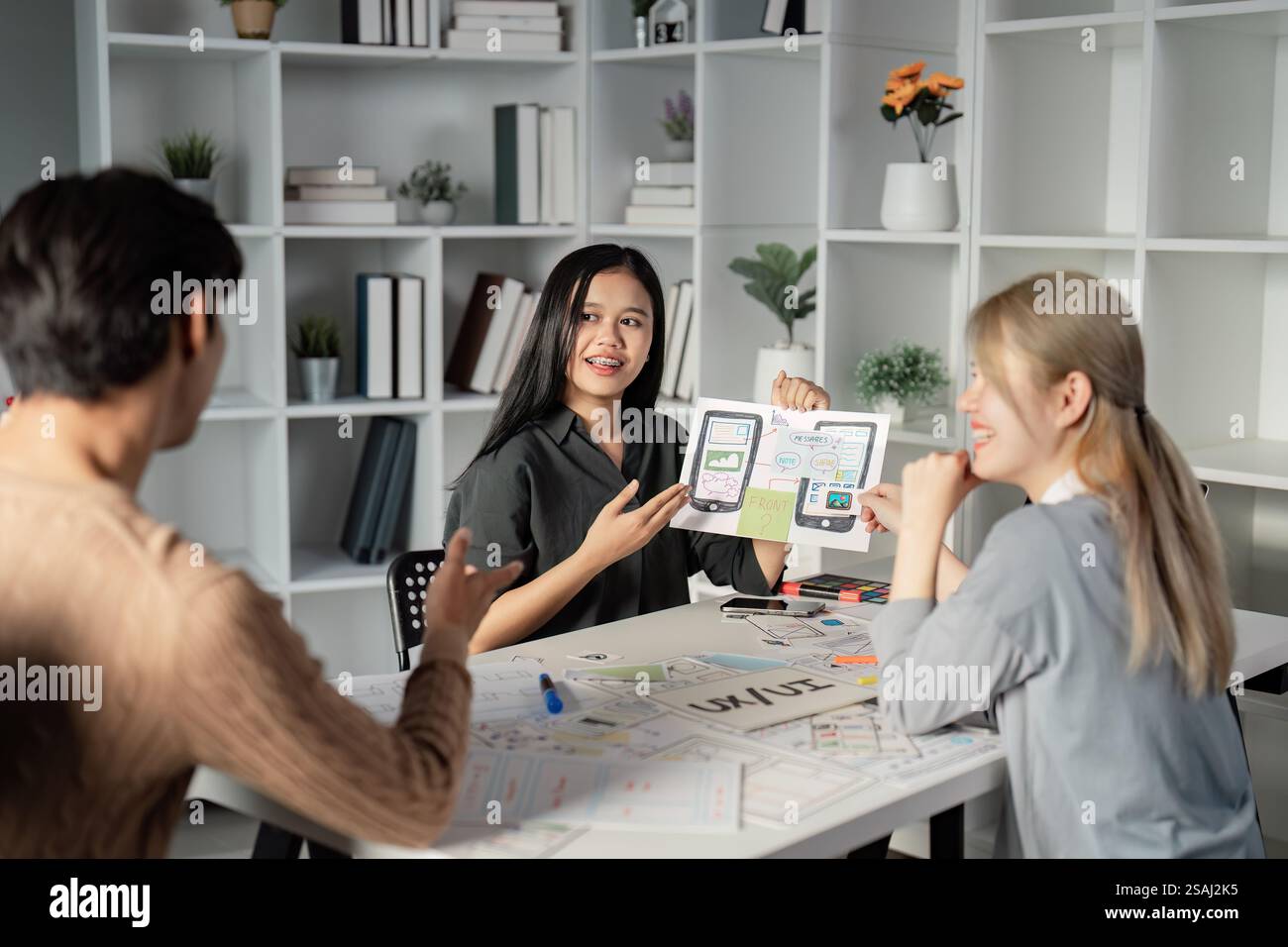 Team collaborating on UX UI presentation with prototypes and sketches ...