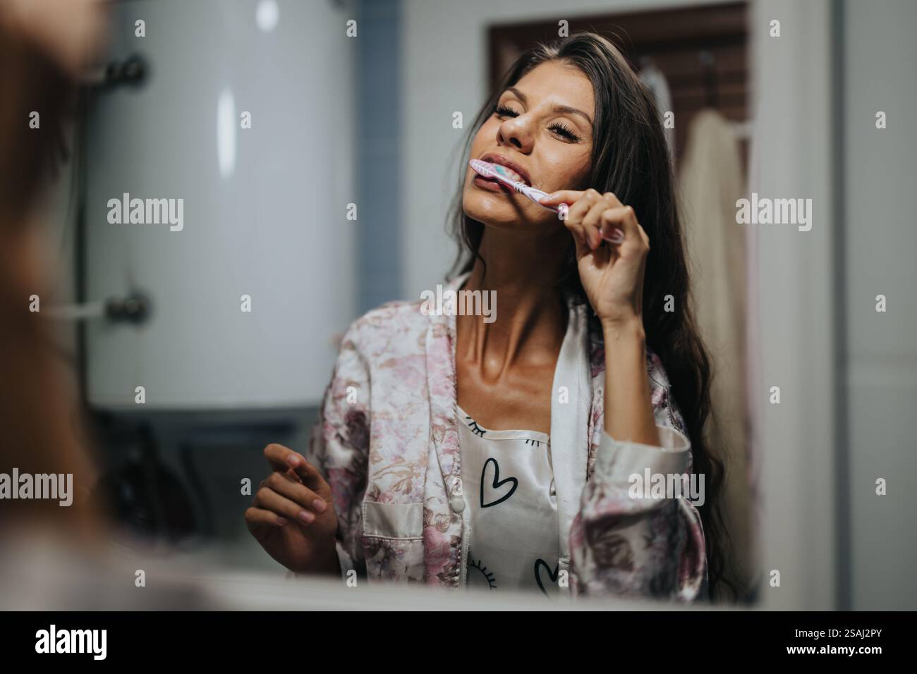 Woman enjoying morning routine of brushing her teeth in bathroom Stock ...