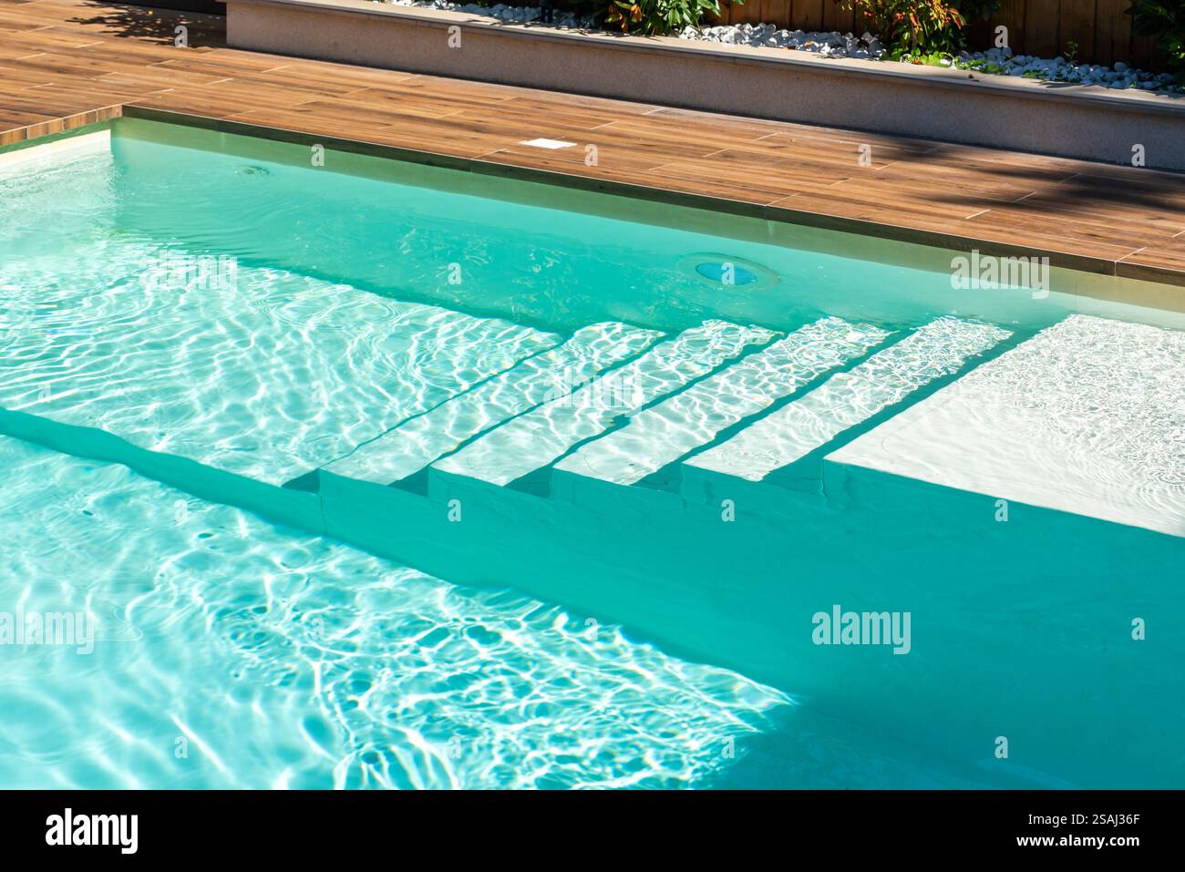 Modern swimming pool with turquoise water, elegant submerged steps, and ...