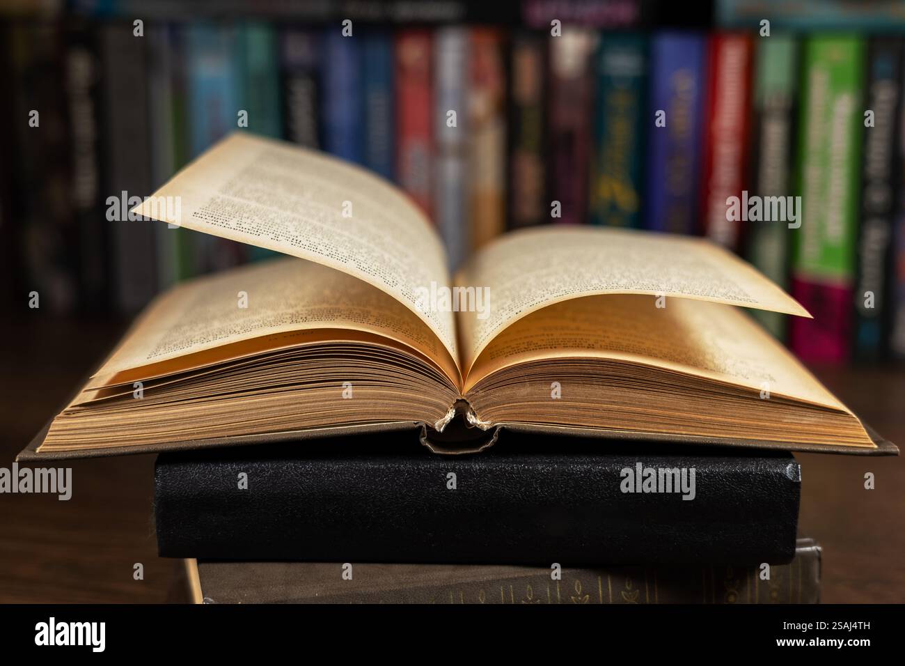 opened book, lying on the bookshelf in library Stock Photo - Alamy