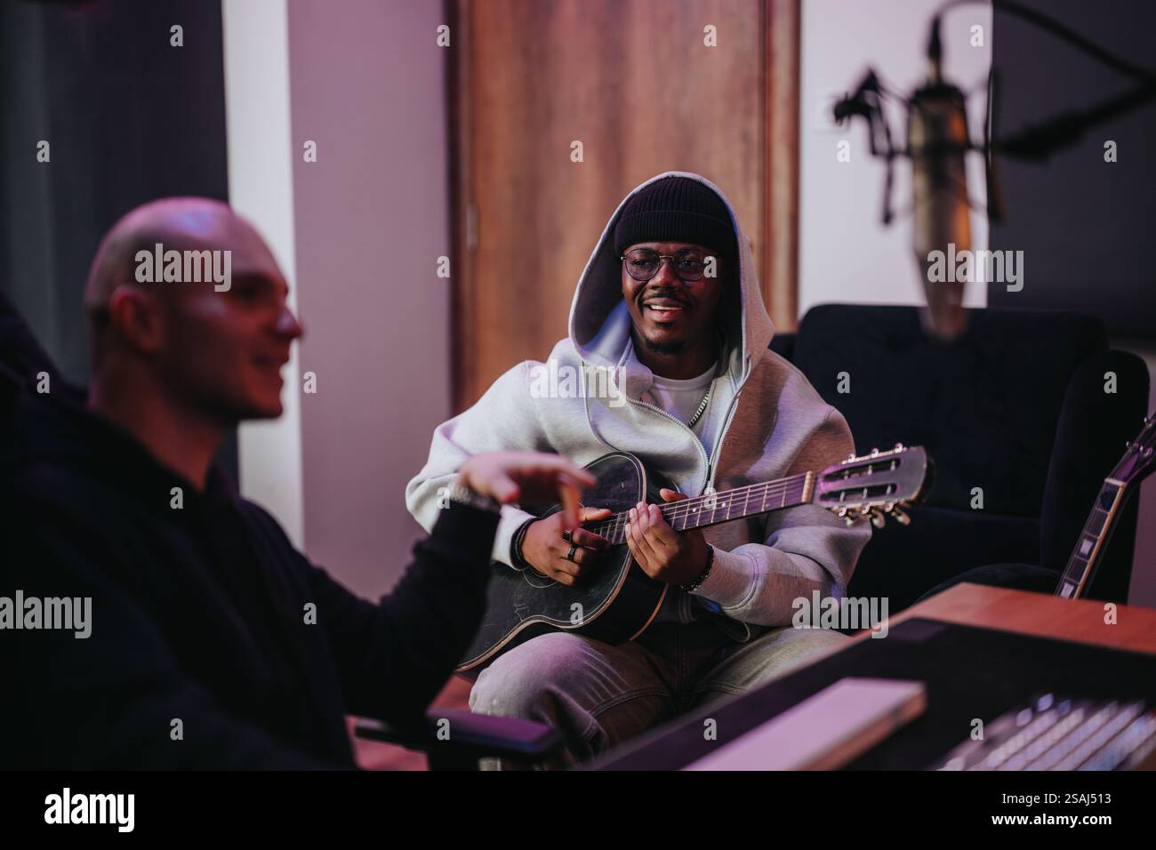 Two musicians collaborate in a modern recording studio with guitar and ...