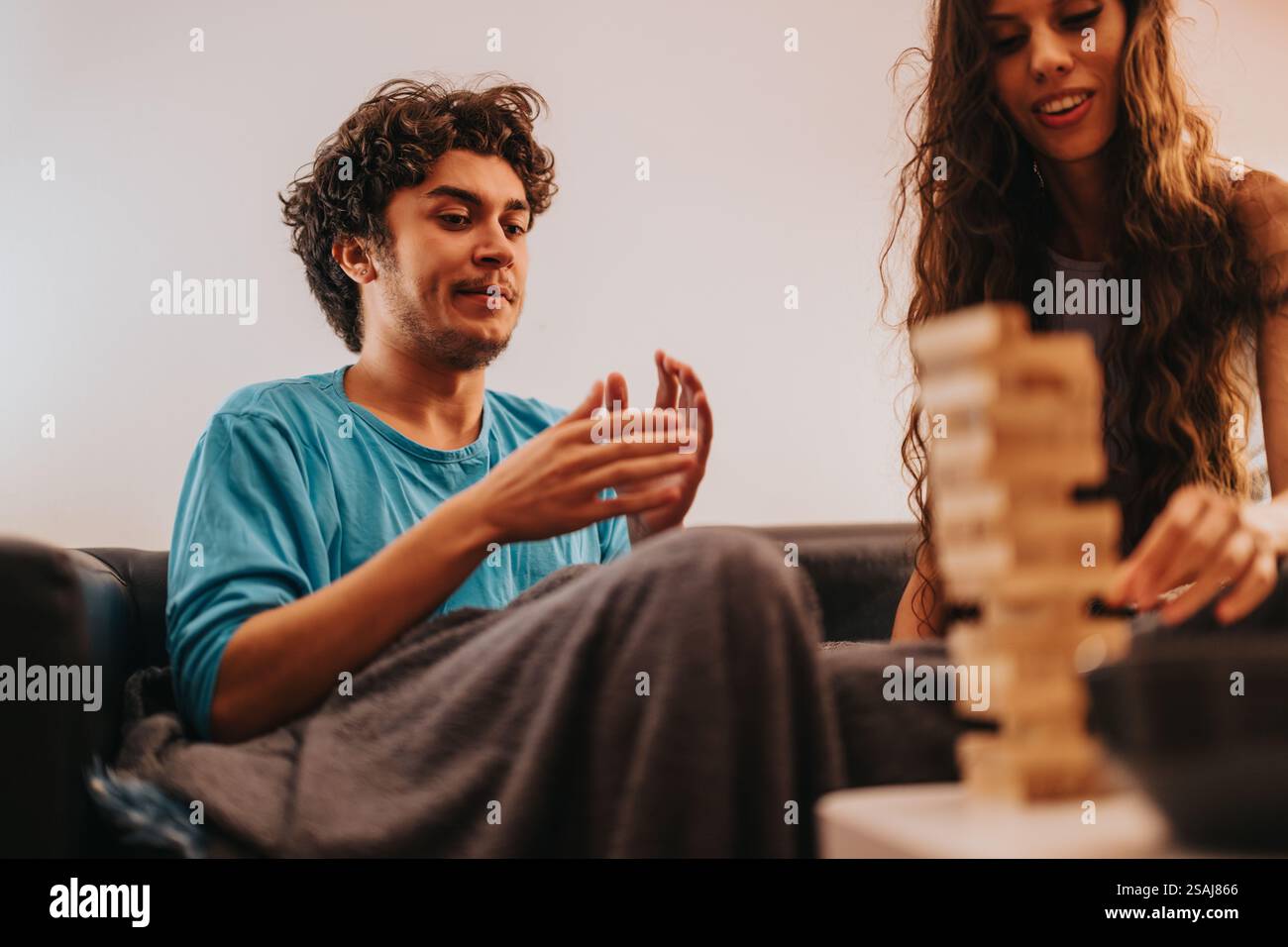 Friends enjoy a game of Jenga indoors on a relaxing day Stock Photo - Alamy