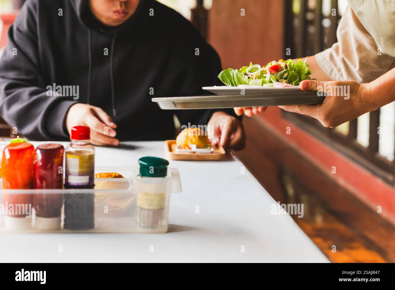 Waitress serving healthy green vegetable salad with bread bun in the ...