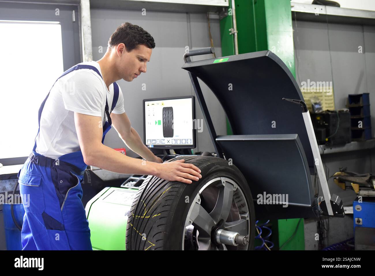 tyre change in a garage - assembler balancing a tyre on the machine ...