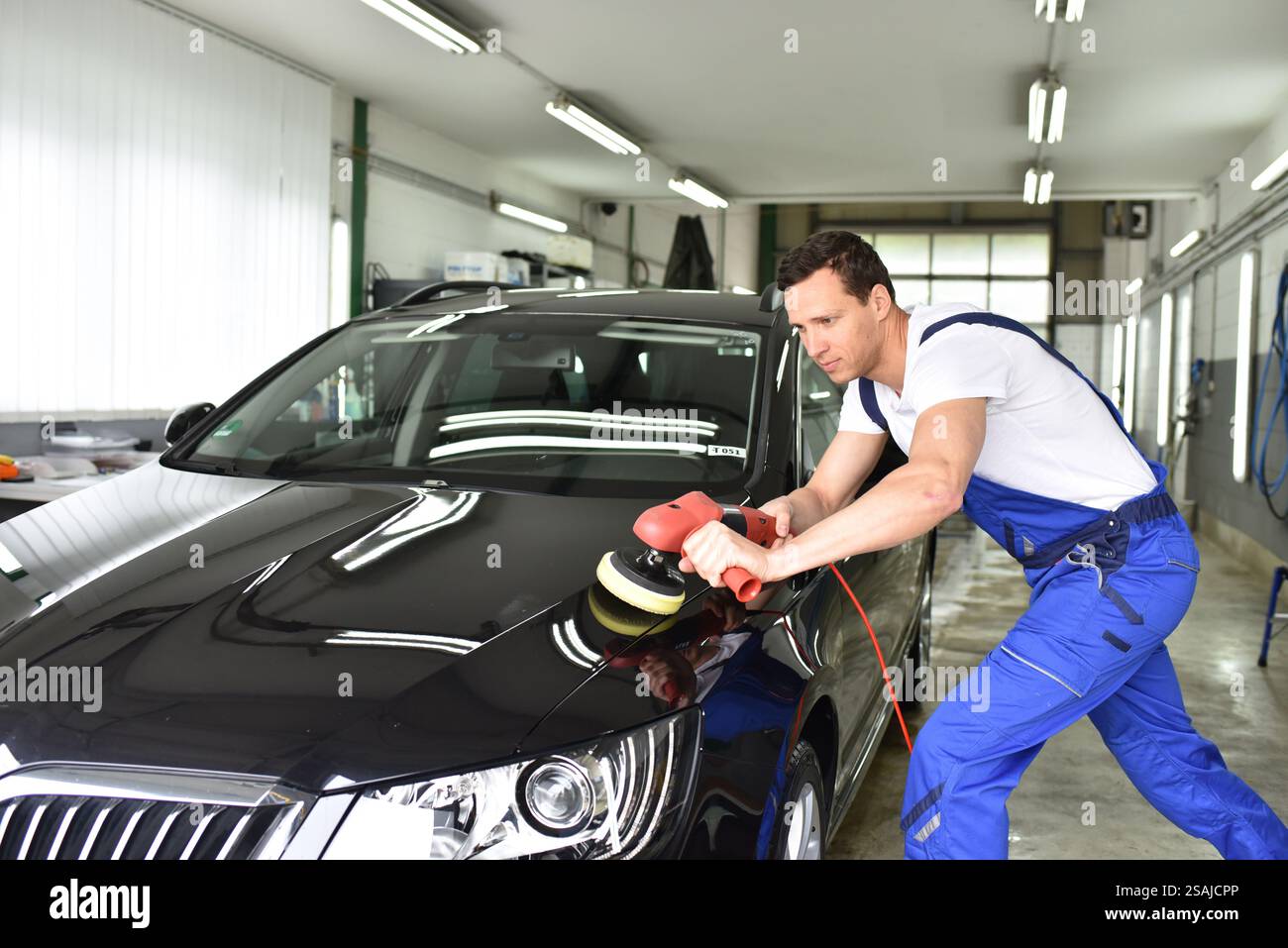 professional car wash - worker in a car dealership polishes the car ...