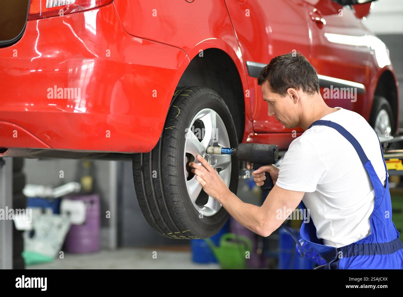 tyre change in a car repair shop - worker assembles rims on the vehicle ...