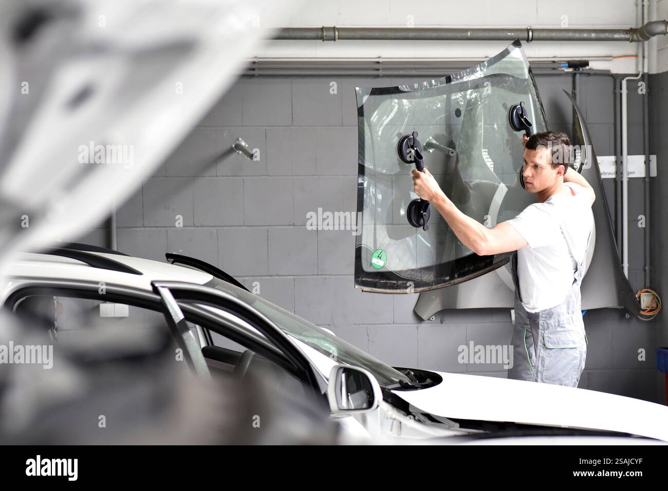 mechanic in a garage replaces defective windshield of a car Stock Photo ...