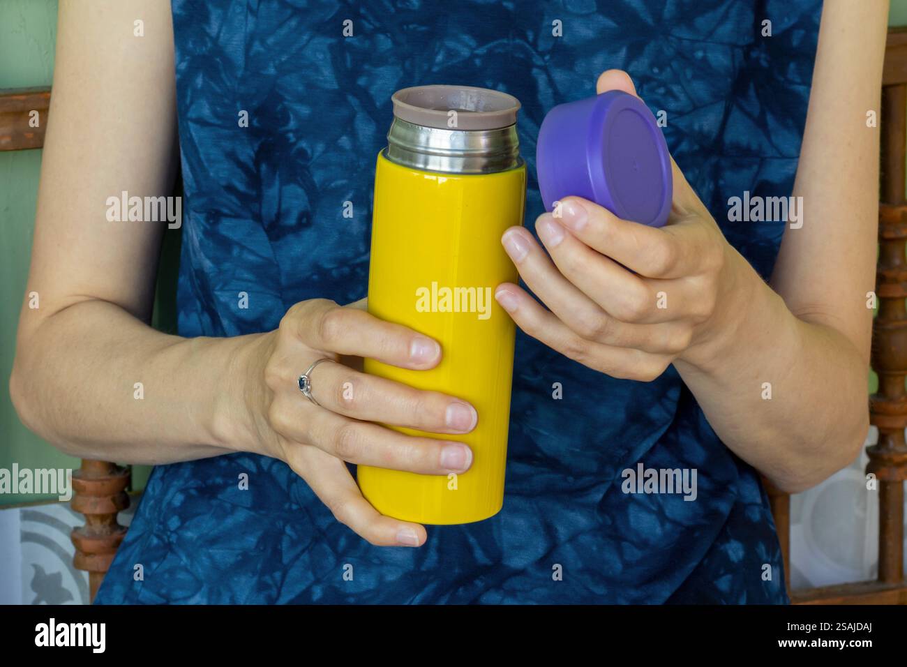 Yellow thermos with violet cap in woman's hands. Close-up ...