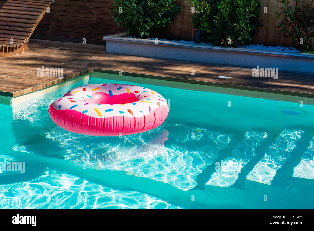 Pink donut inflatable float in turquoise swimming pool with submerged ...