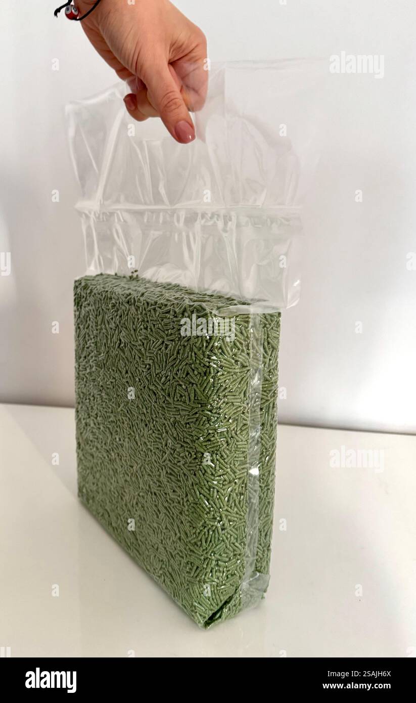 Female hand holding a transparent plastic bag with tofu litter pellets ...