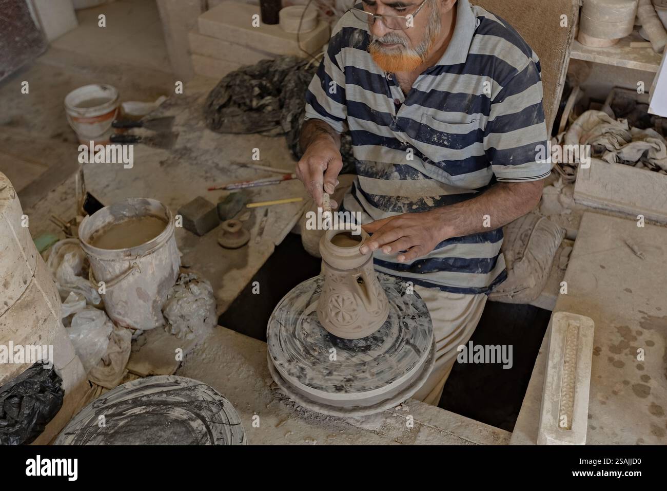 Man at pottery workshop. Arab man producing pitcher from clay at ...