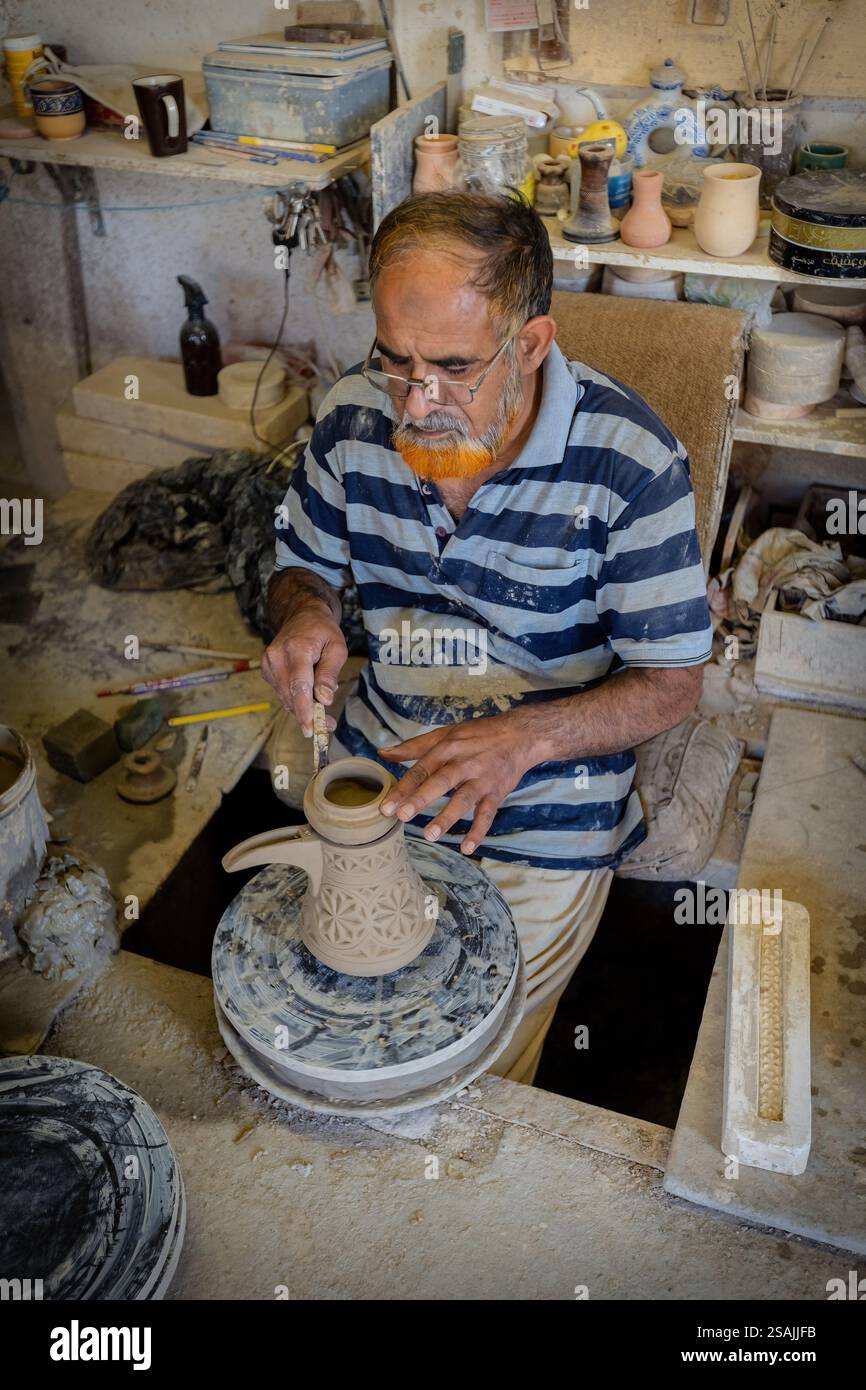 Man at pottery workshop. Arab man producing pitcher from clay at ...