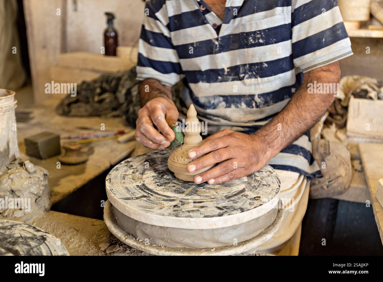 Man at pottery workshop. Arab man producing pitcher from clay at ...