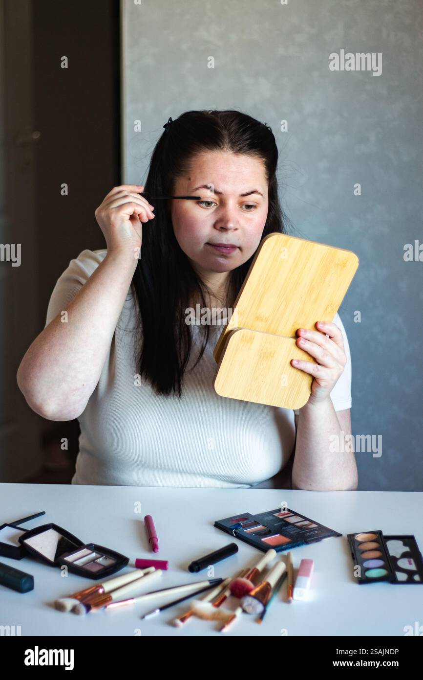 Vertical image of Millennial Caucasian woman doing self make up ...