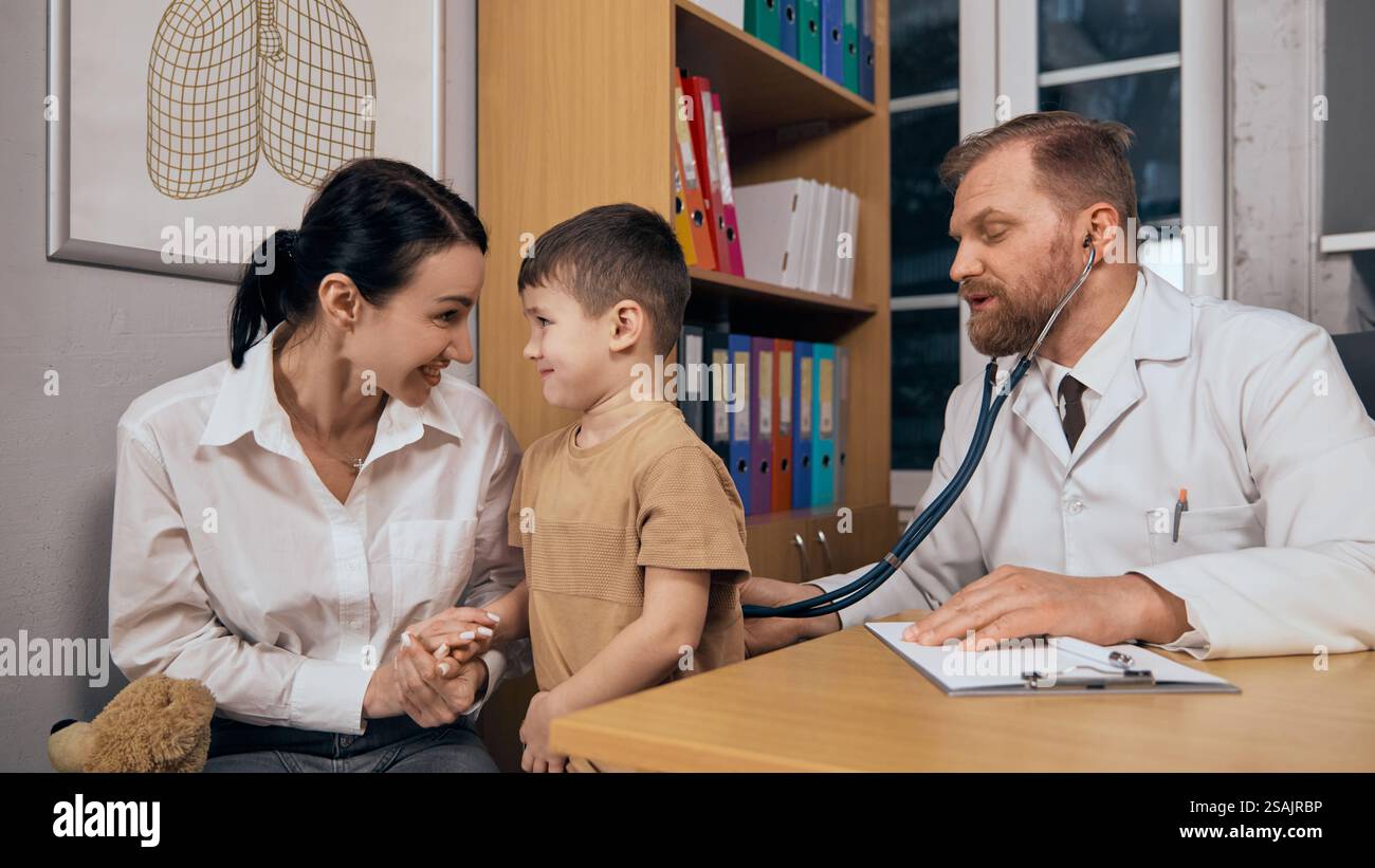 Smiling mother supporting her child while doctor checking his breath ...