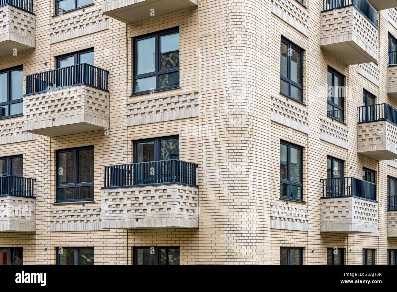 Modern beige brick building with multiple balconies with metal railings ...