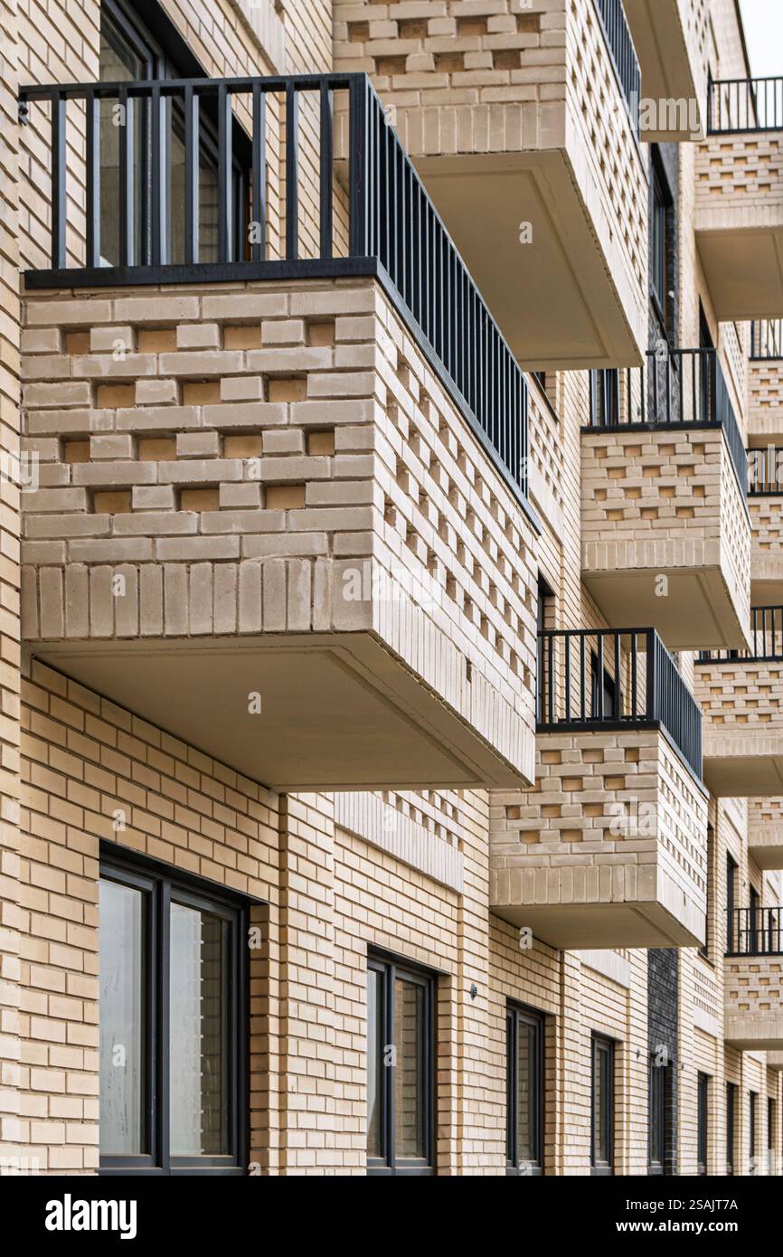 Modern beige brick building with multiple balconies with metal railings ...