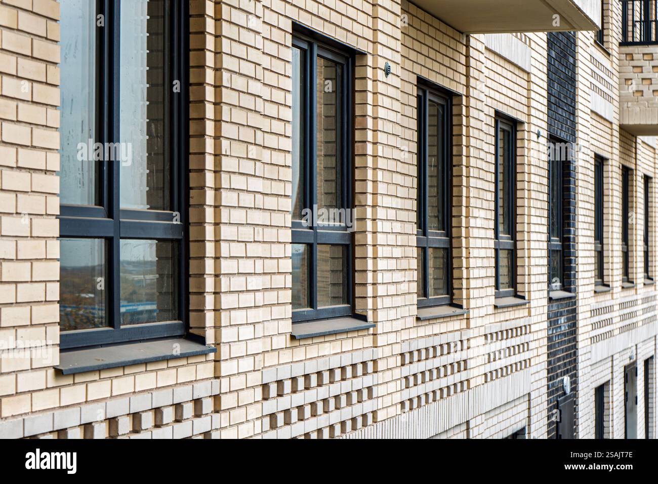 Exterior facade of a beige brick building featuring large dark-framed ...
