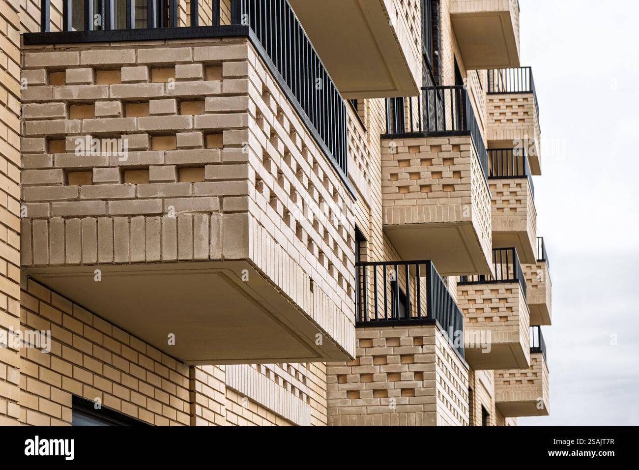 Modern beige brick building with multiple balconies with metal railings ...