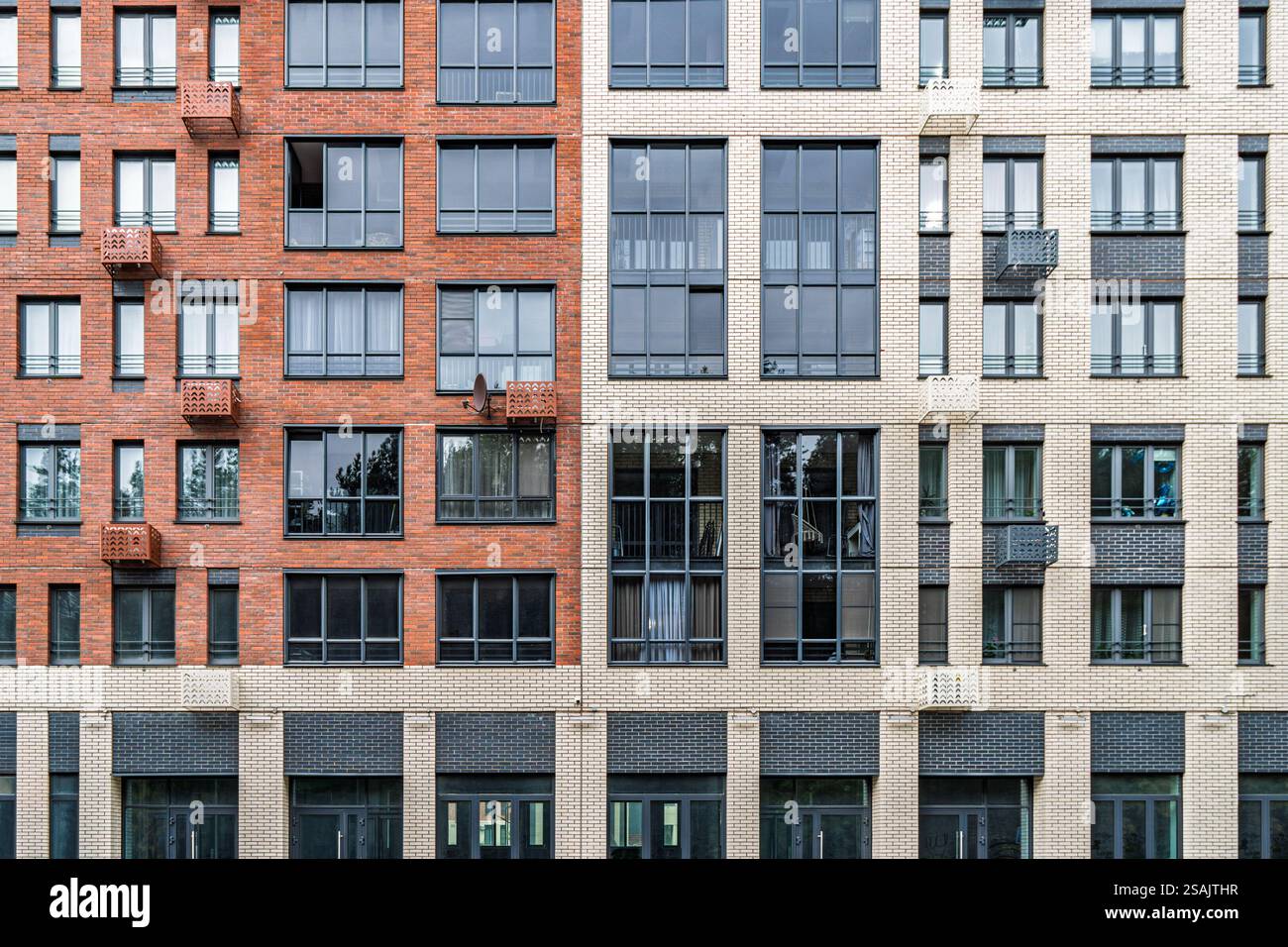 Contemporary multi-story buildings with beige, red brick and glass facades, showcasing balconies ...
