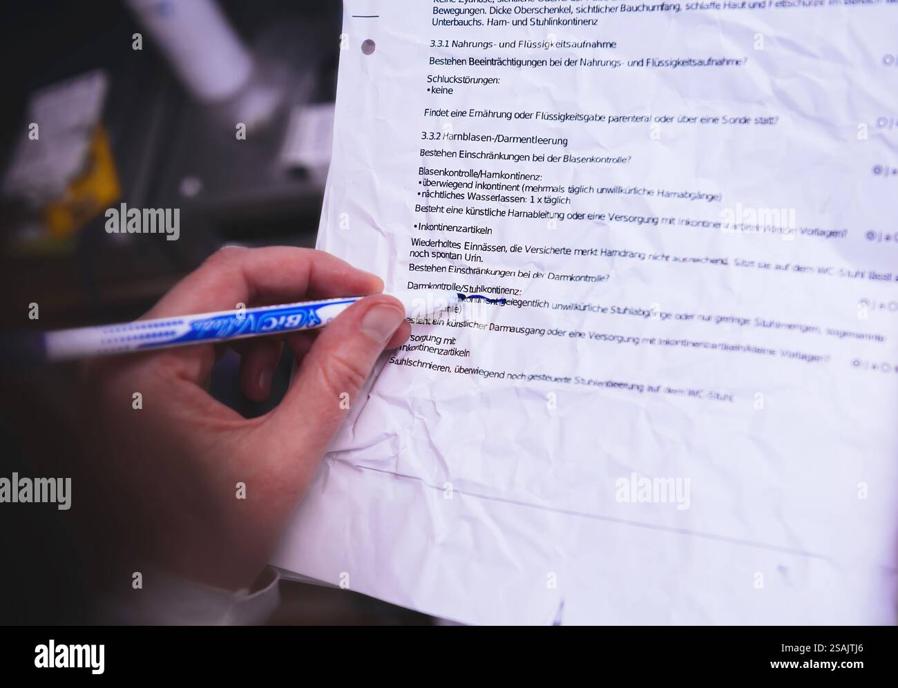 A doctor marks answers on a German medical form focused on assessing ...