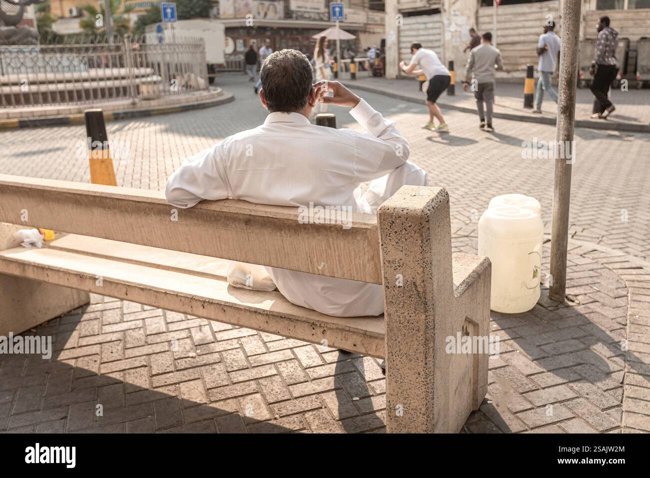 Arab man talking on the phone on the bench back view Manama Bahrain ...