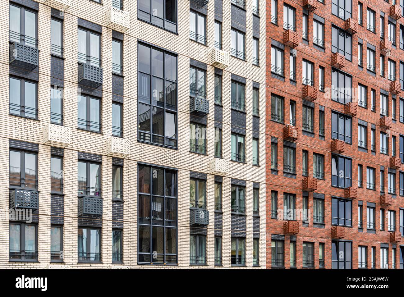 Contemporary multi-story buildings with beige, red brick and glass facades, showcasing balconies ...