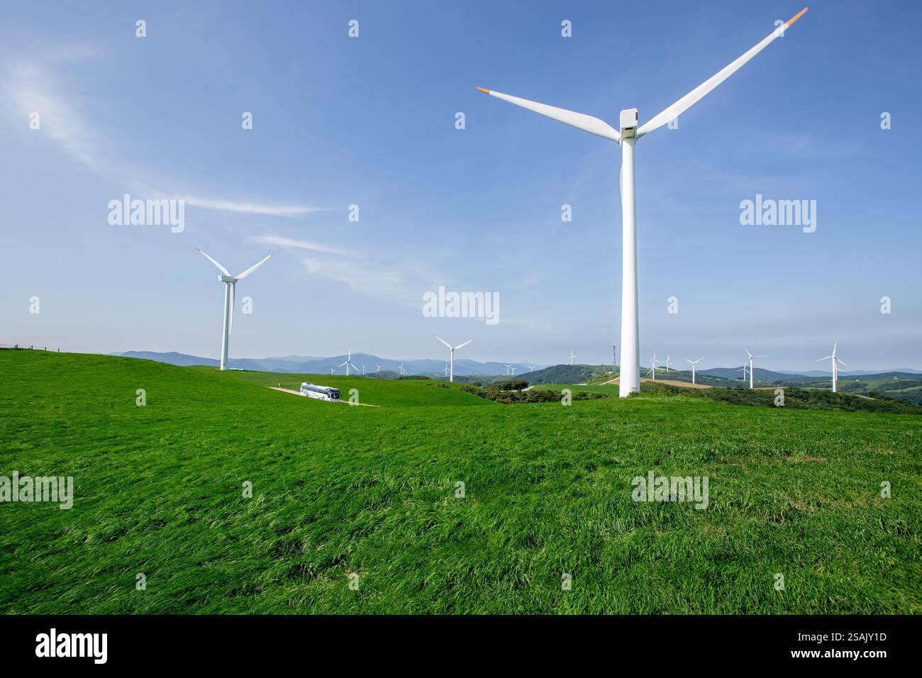 Bus running on pastures and wind farms spread out under the blue sky ...