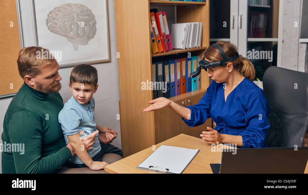 Female doctor explaining health details to father holding young boy ...