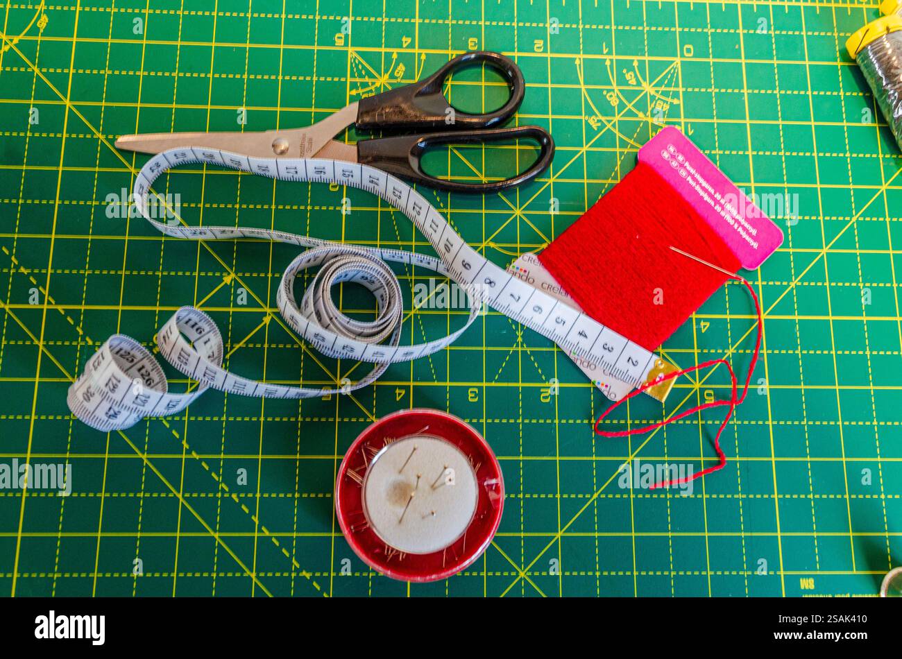 Collection of items used in a sewing kit on a cutting mat background ...