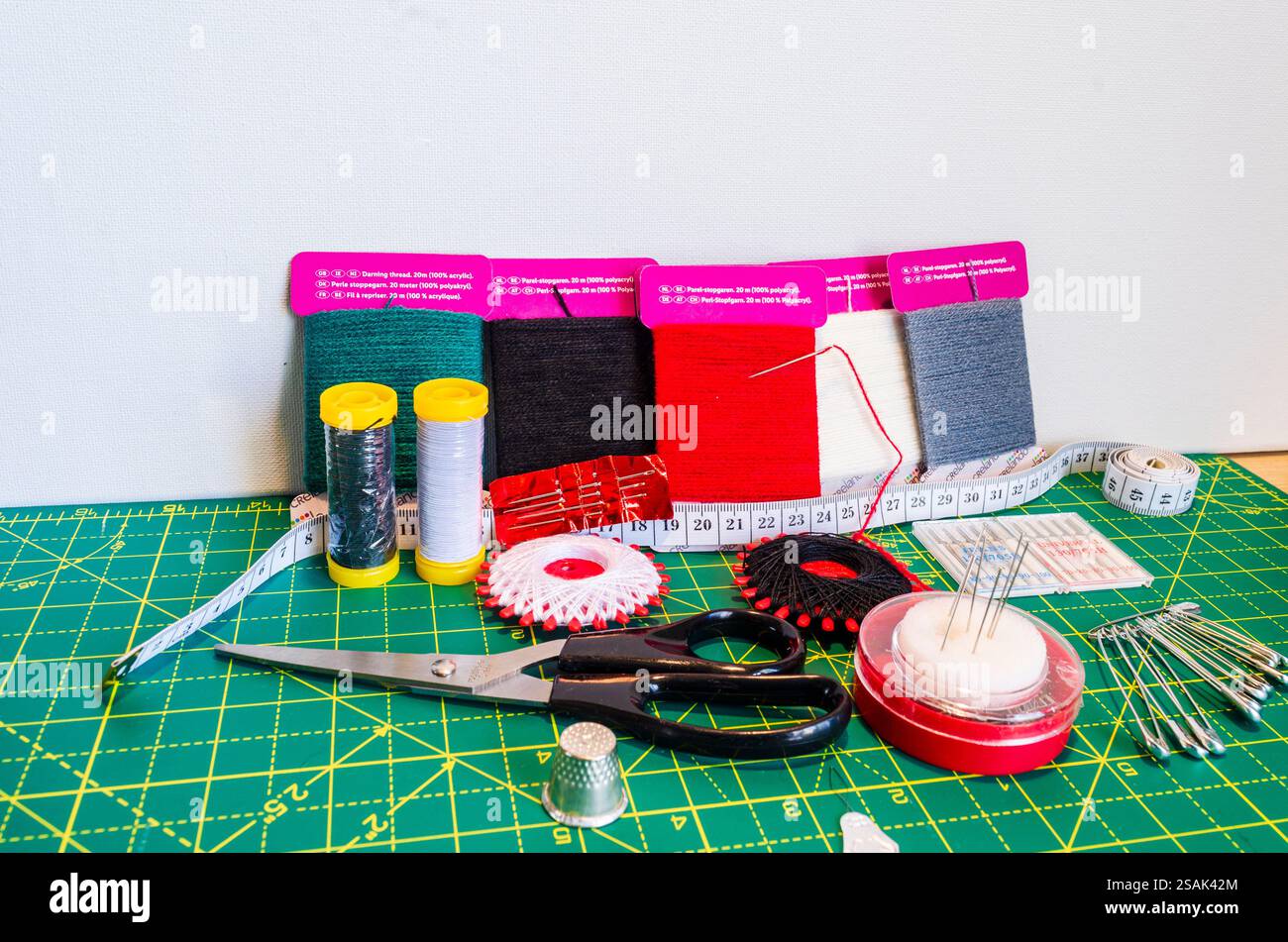 Collection of items used in a sewing kit on a cutting mat with white ...