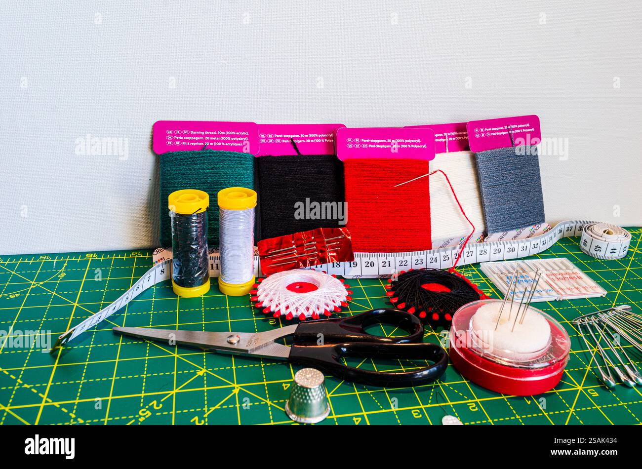 Collection of items used in a sewing kit on a cutting mat with white ...