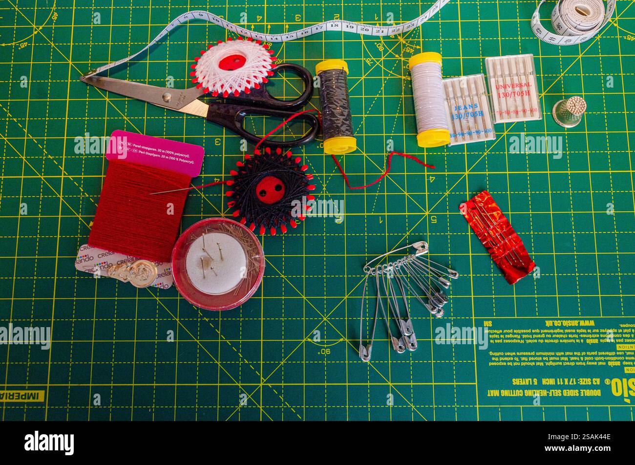 Collection of items used in a sewing kit on a cutting mat background ...