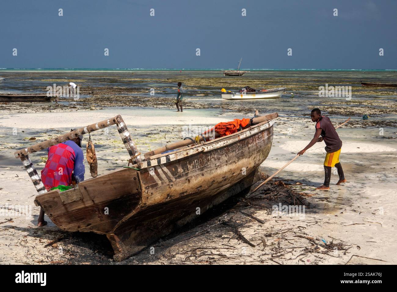 Africa Tanzania, Zanzibar, Nungwi, beach, man raking ashes of palm ...