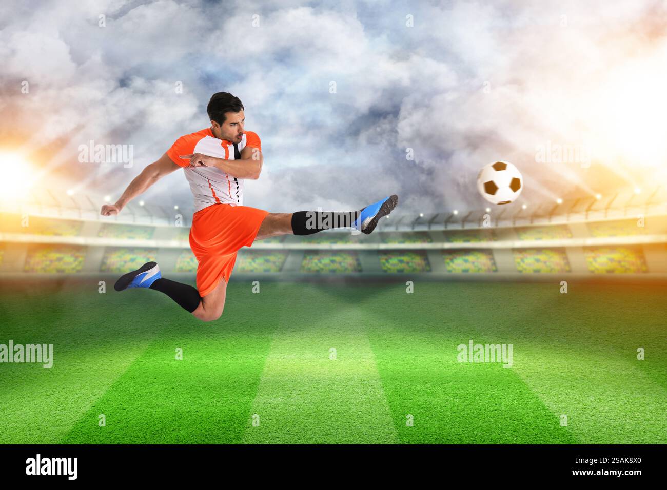 Young man playing football under lights at stadium Stock Photo - Alamy