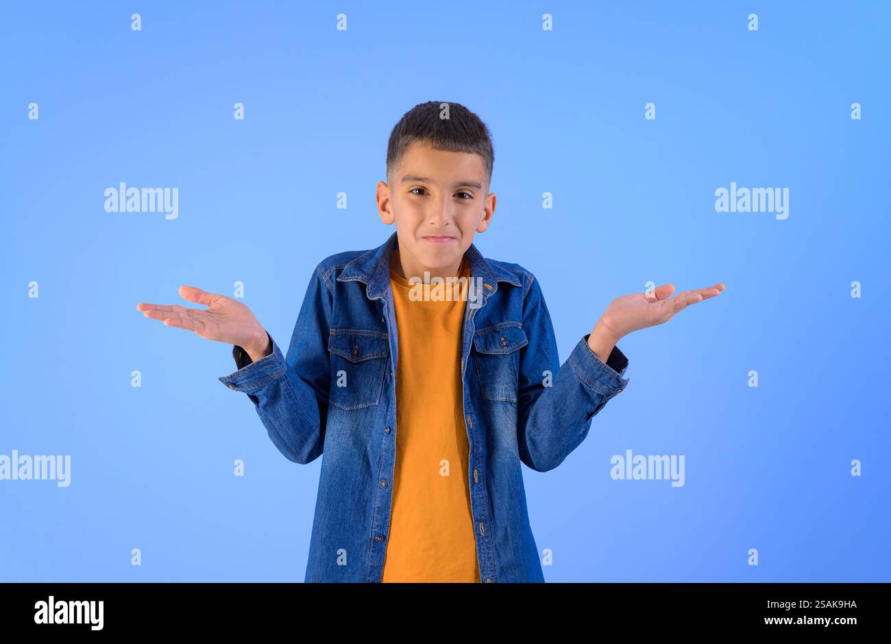 Portrait of confused young boy shrugging shoulders while standing ...