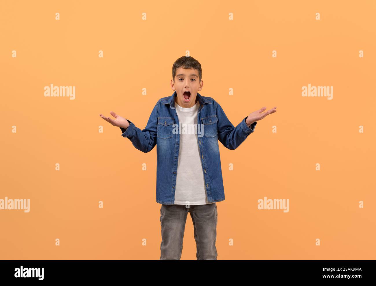 Portrait of confused shocked boy with mouth open and arms outstretched ...