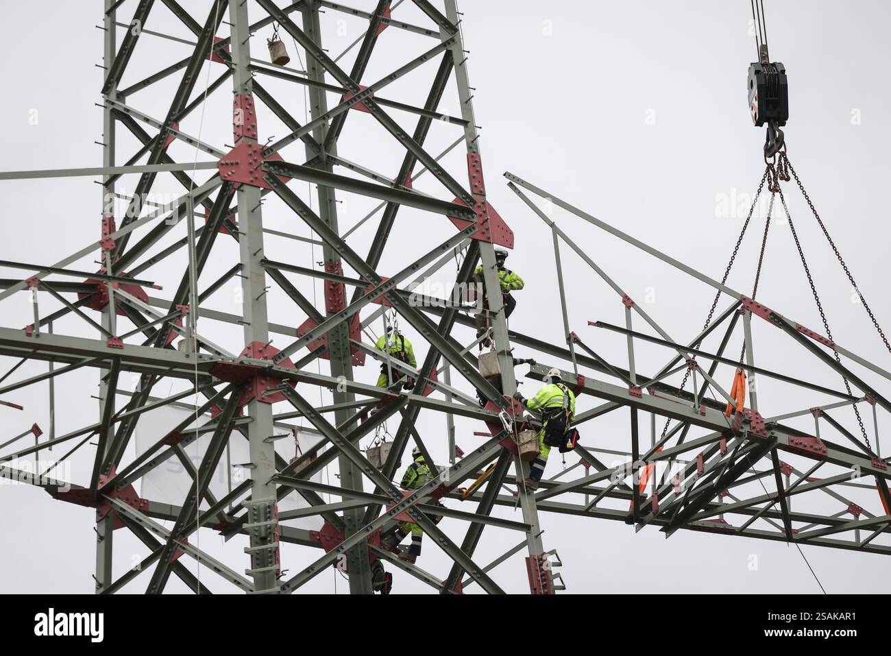 Altenkrempe, Germany. 30th Jan, 2025. Employees of a specialist company assemble a pylon for the ...