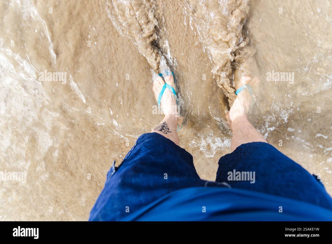 Top view of shod feet in the water at the beach. relaxation concept ...